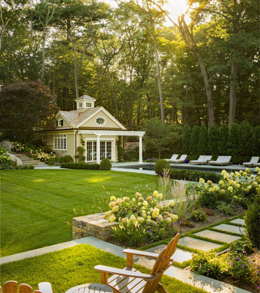 Shingle-Clad Pool House at the Edge of a Lush Backyard Oasis